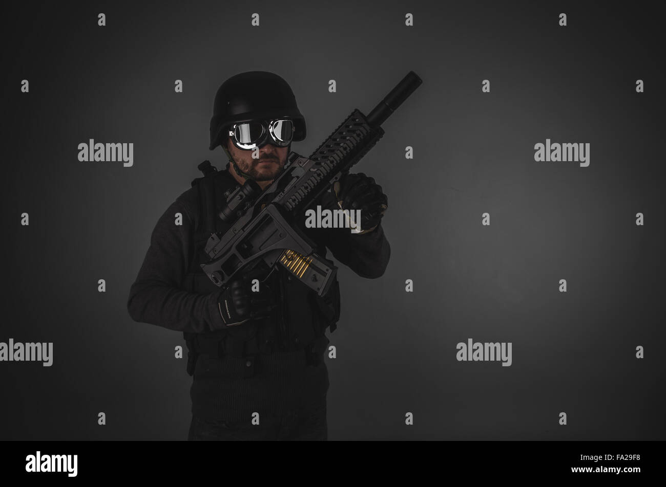 airsoft player with gun, helmet and bulletproof vest on gray background ...