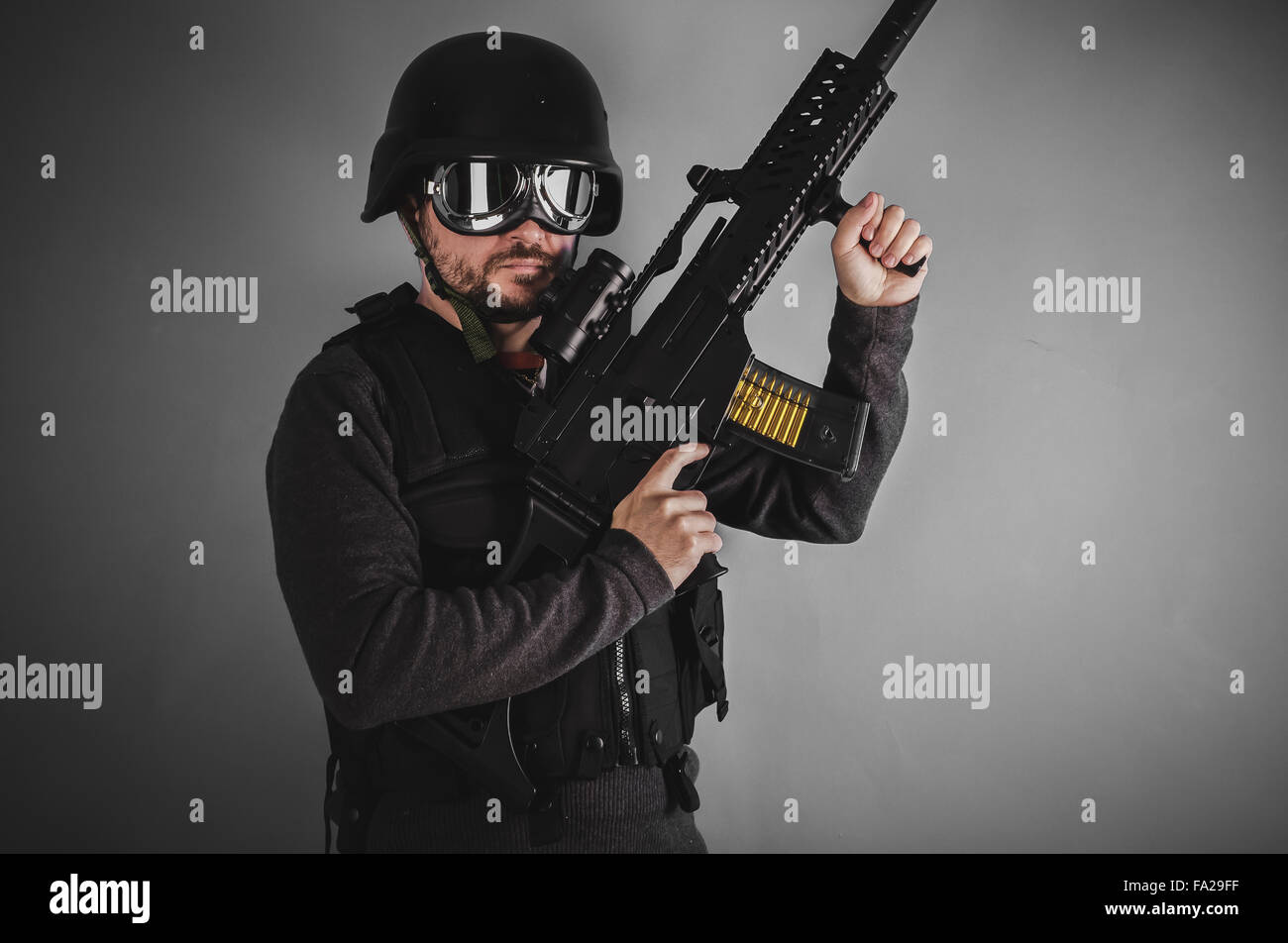 airsoft player with gun, helmet and bulletproof vest on gray background ...