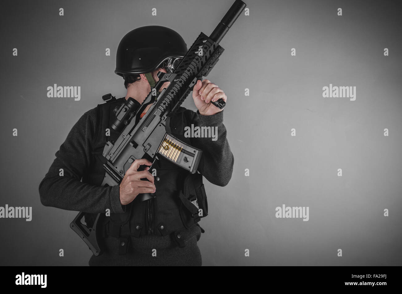 gunpowder, airsoft player with gun, helmet and bulletproof vest on gray ...