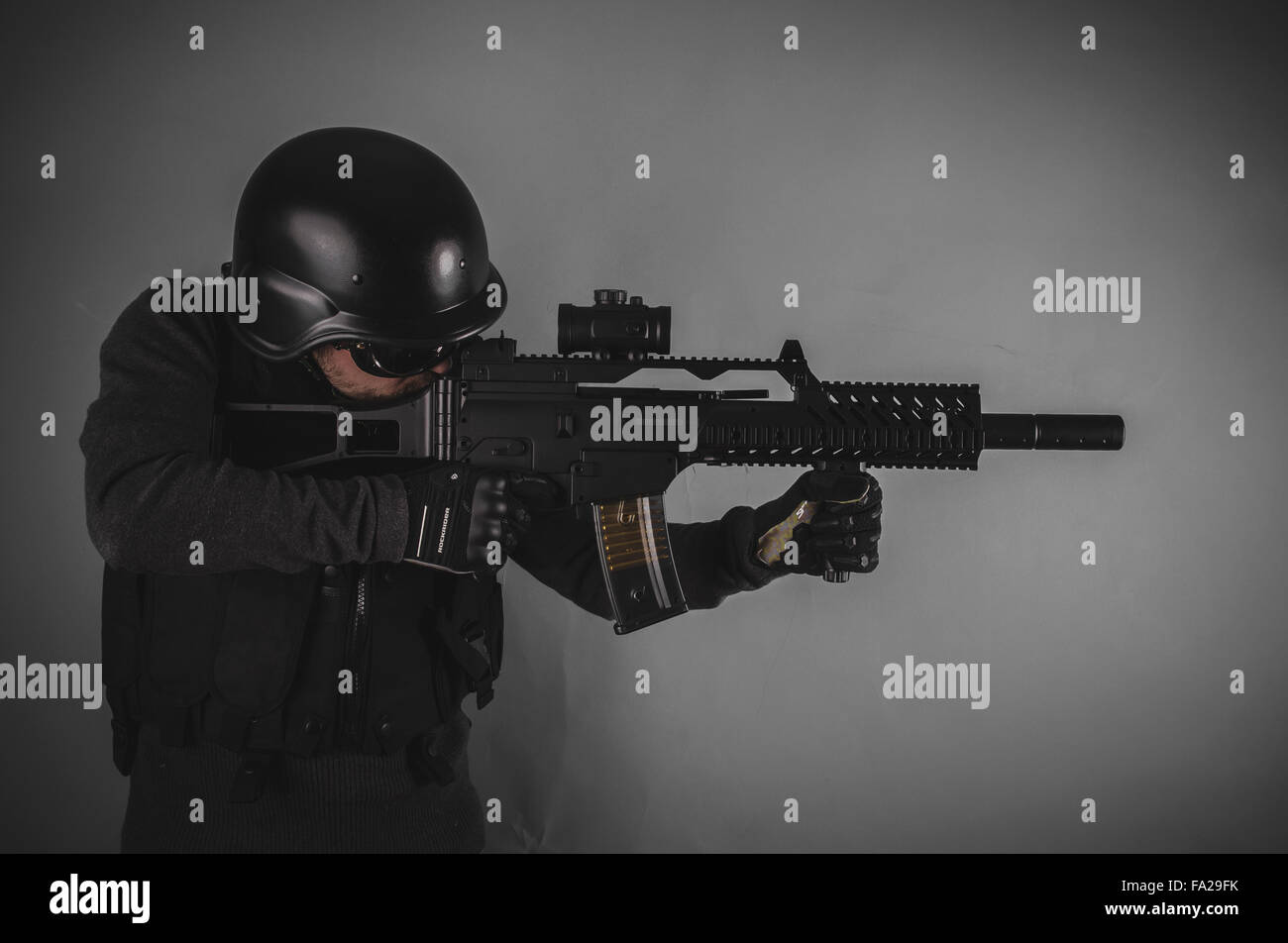 sniper, airsoft player with gun, helmet and bulletproof vest on gray ...