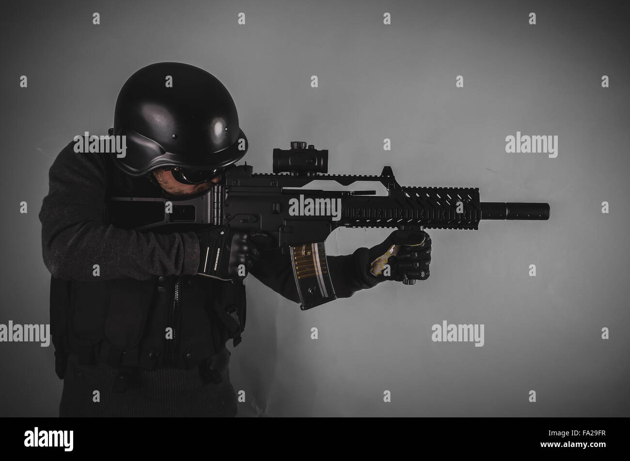 sniper, airsoft player with gun, helmet and bulletproof vest on gray ...