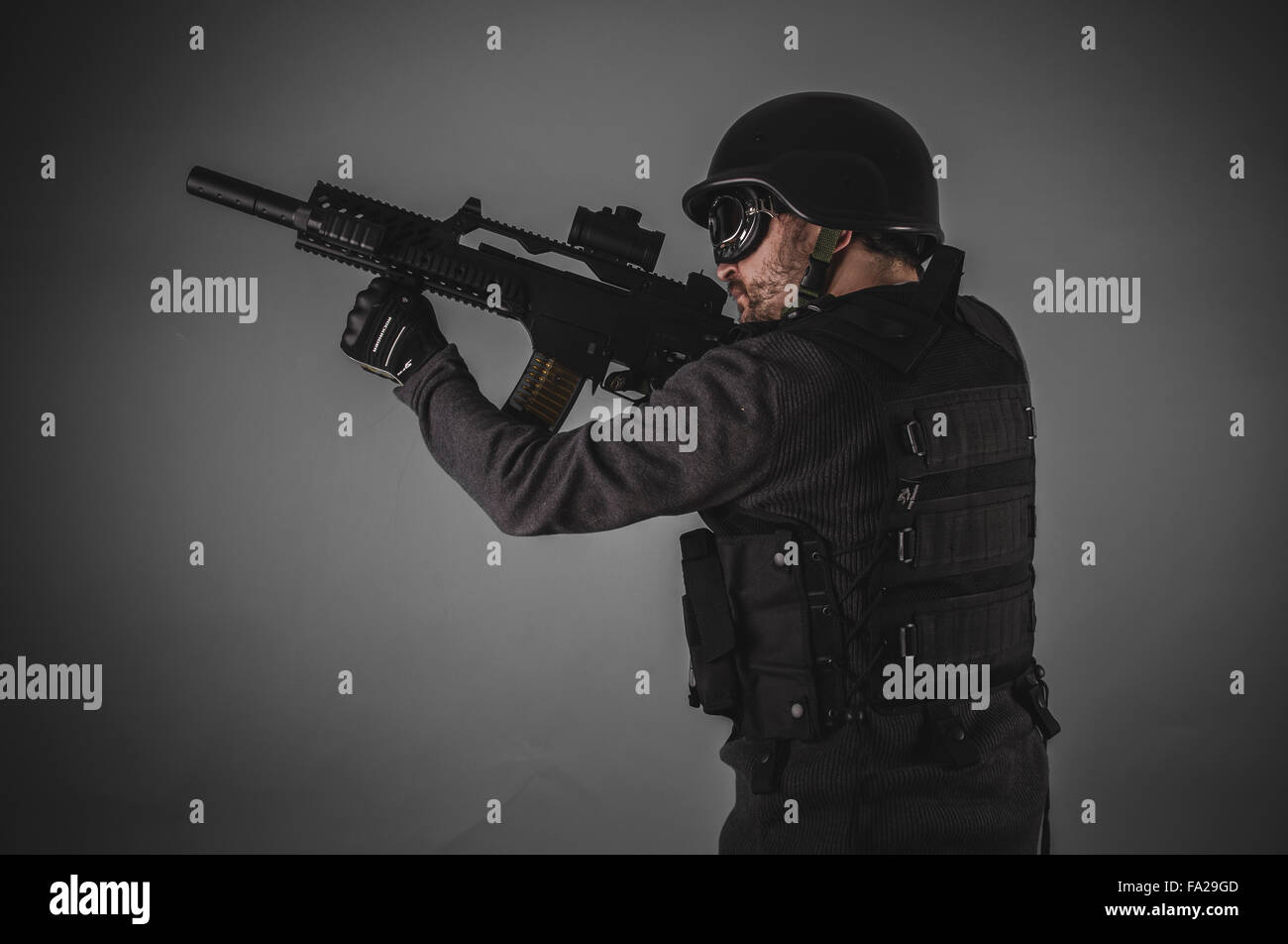 shooting, airsoft player with gun, helmet and bulletproof vest on gray ...