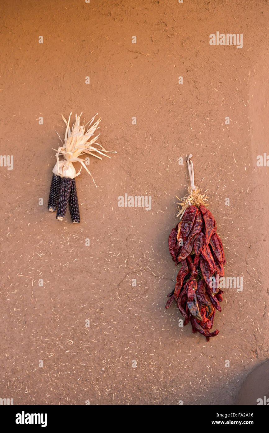 Dried maize and chile peppers hang on an adobe wall at the ancient ...