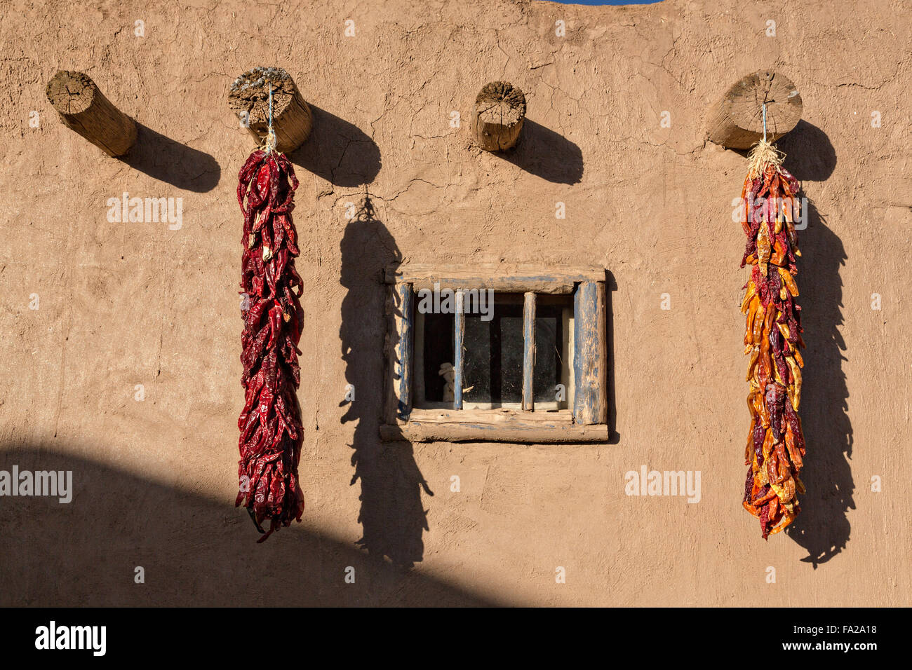 Dried chile pepper ristras hang on an adobe wall at the ancient Native ...