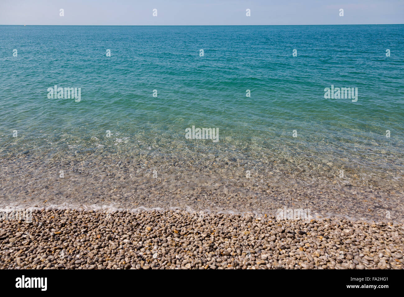 A shingle beach and clear ocean water Stock Photo - Alamy