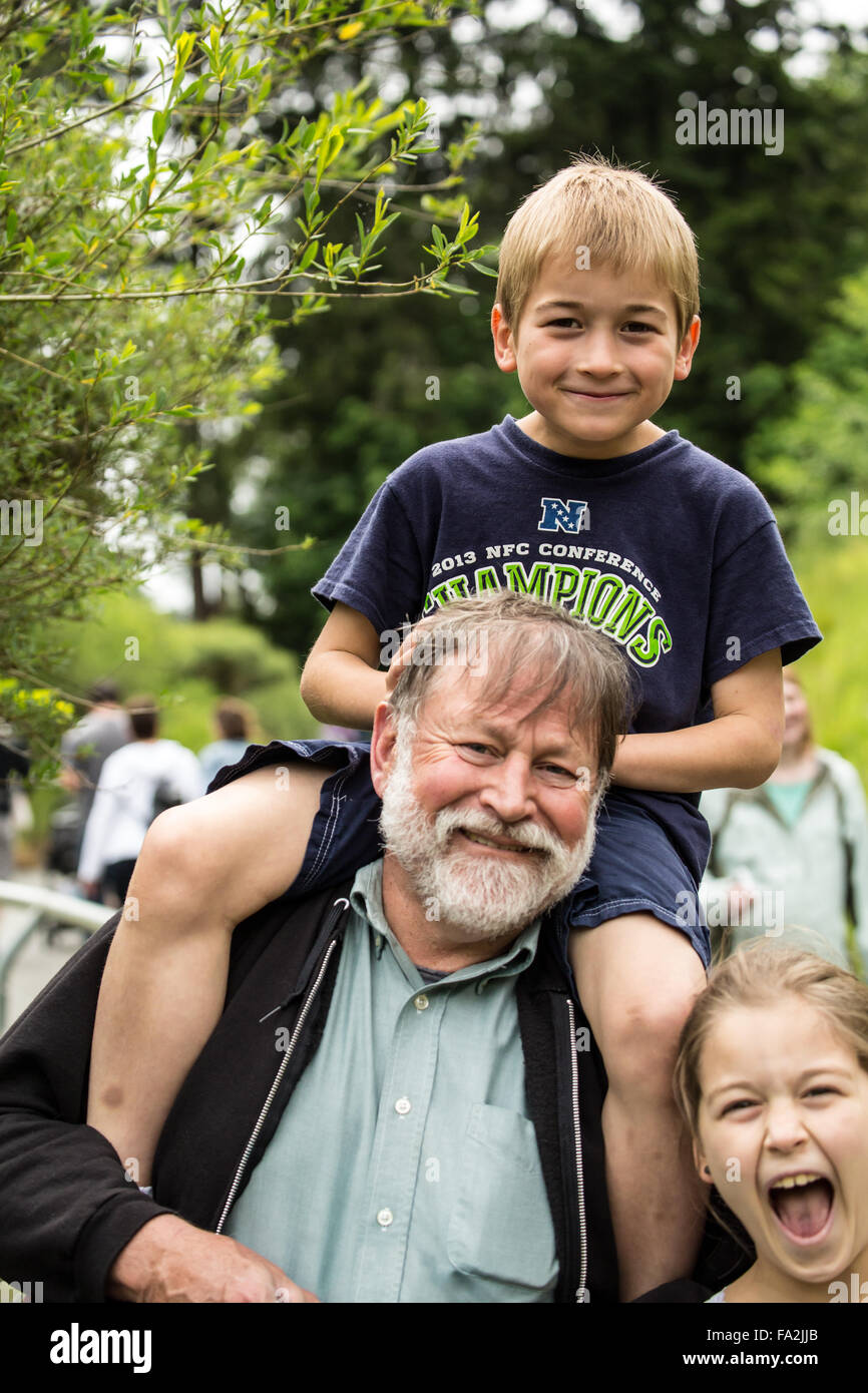 Seven year old boy getting a piggyback ride from his grandfather, with ...