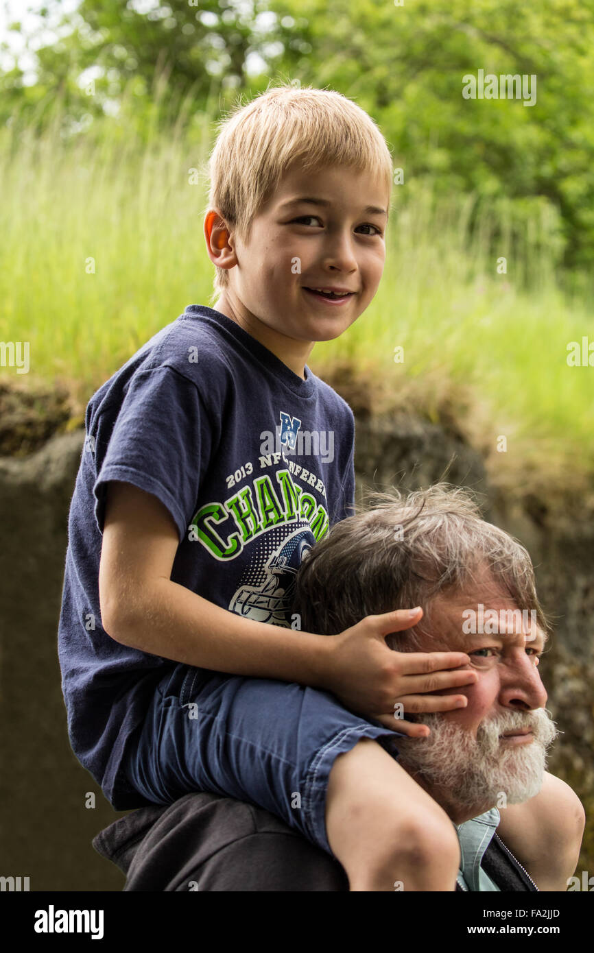 Seven year old boy getting a piggyback ride from his grandfather in ...