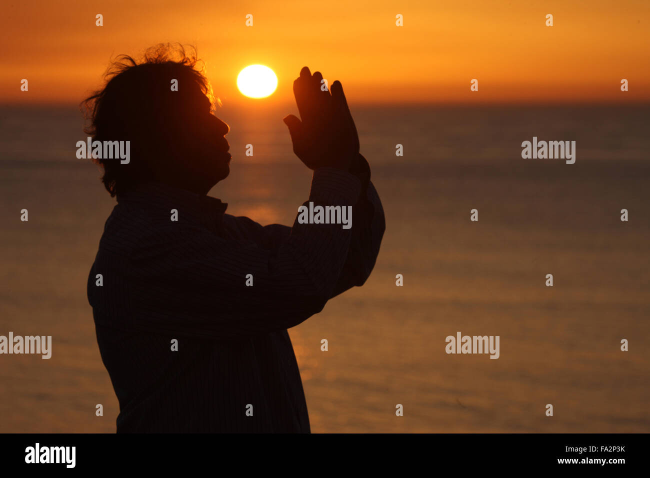 Praying at the seaside. Sunset Stock Photo - Alamy