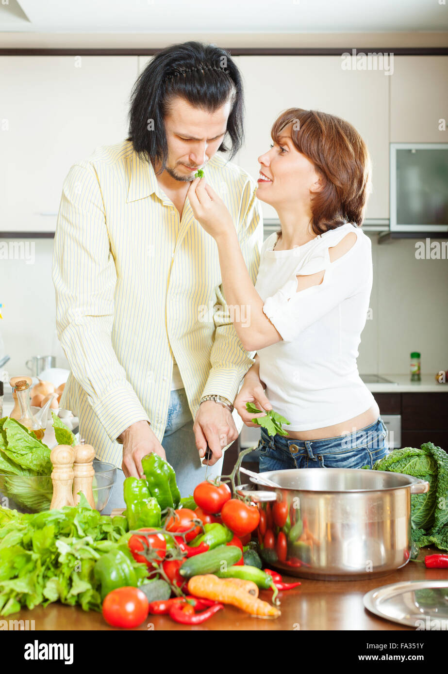 Flirting couple cooking with vegetables in home kitchen Stock Photo - Alamy