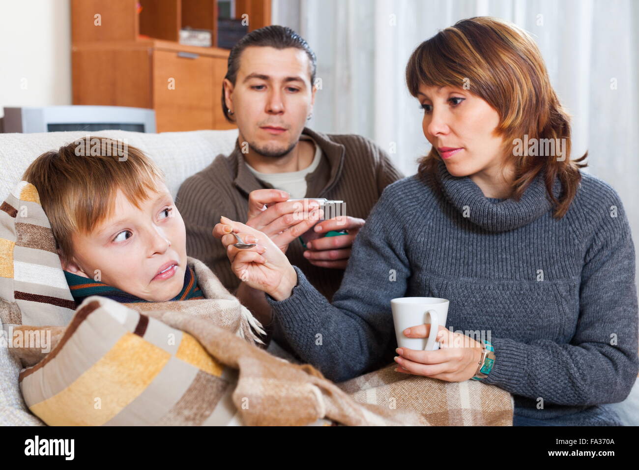 Adult couple and sick boy with thermometer at home Stock Photo - Alamy