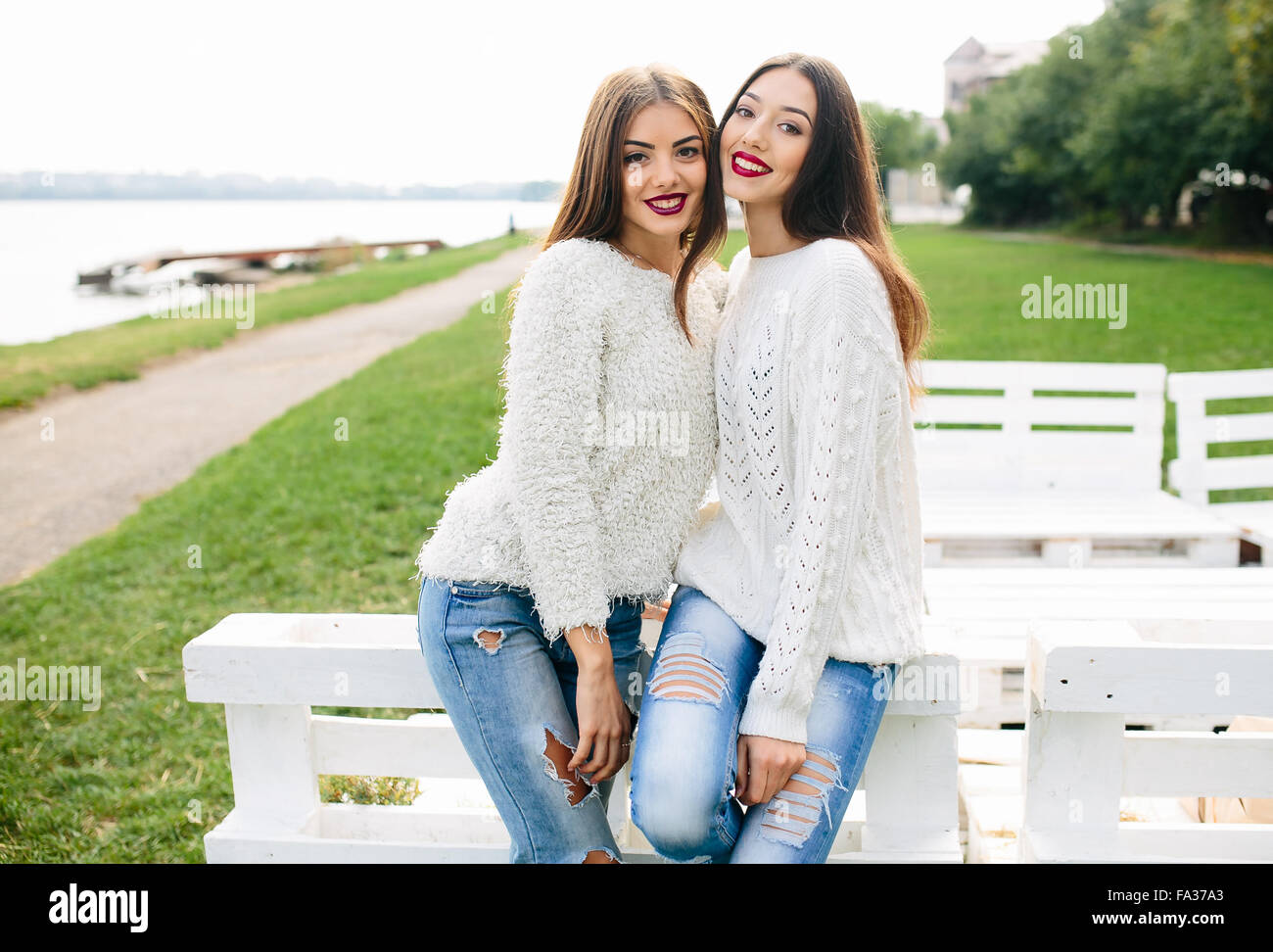 Two girls lean bench Stock Photo - Alamy
