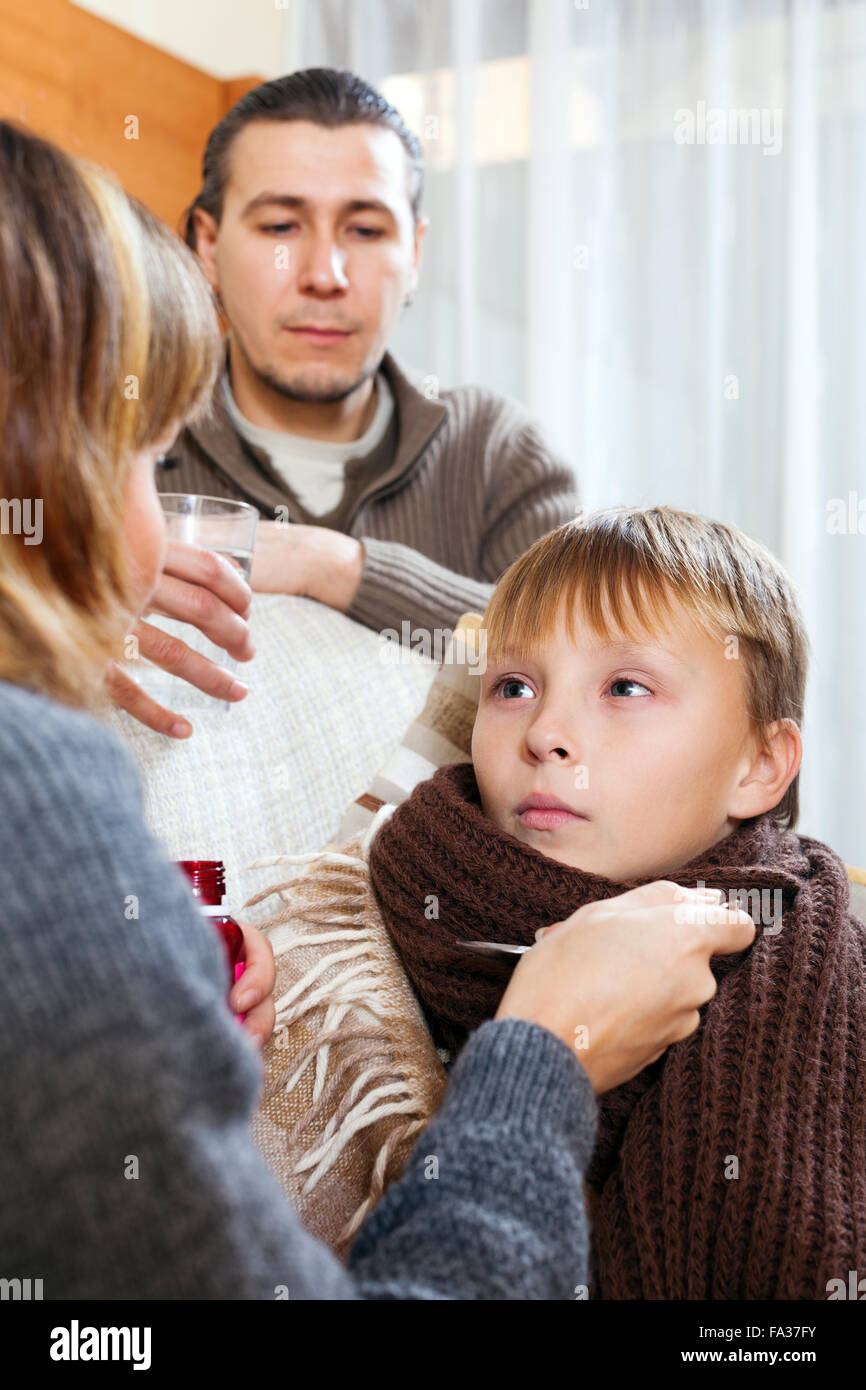 caring parents giving medicinal sirup to teenage son at home Stock ...