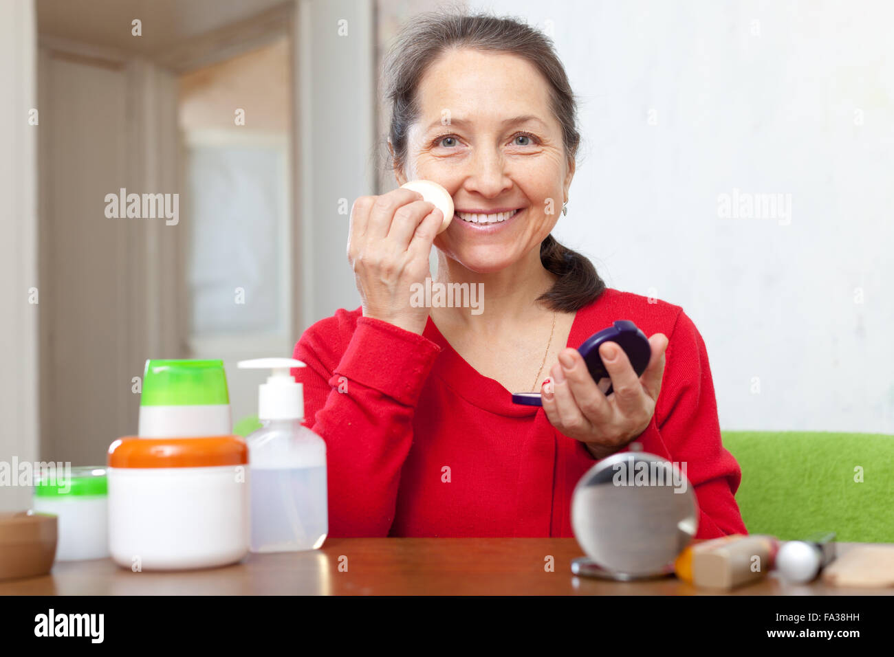 Happy mature woman in dress puts facepowder on her face Stock Photo - Alamy