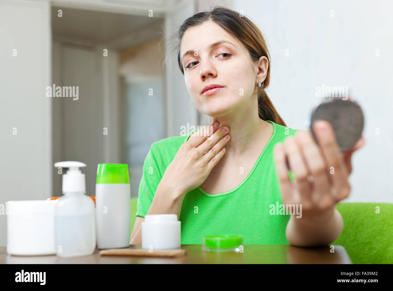 woman in green stares on her neck in mirror at home Stock Photo - Alamy
