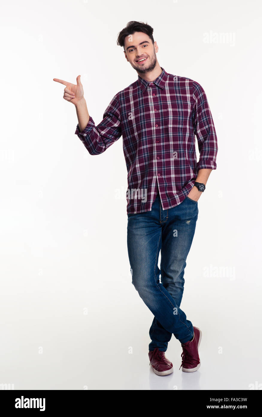 Full length portrait of a smiling man pointing finger away isolated on ...