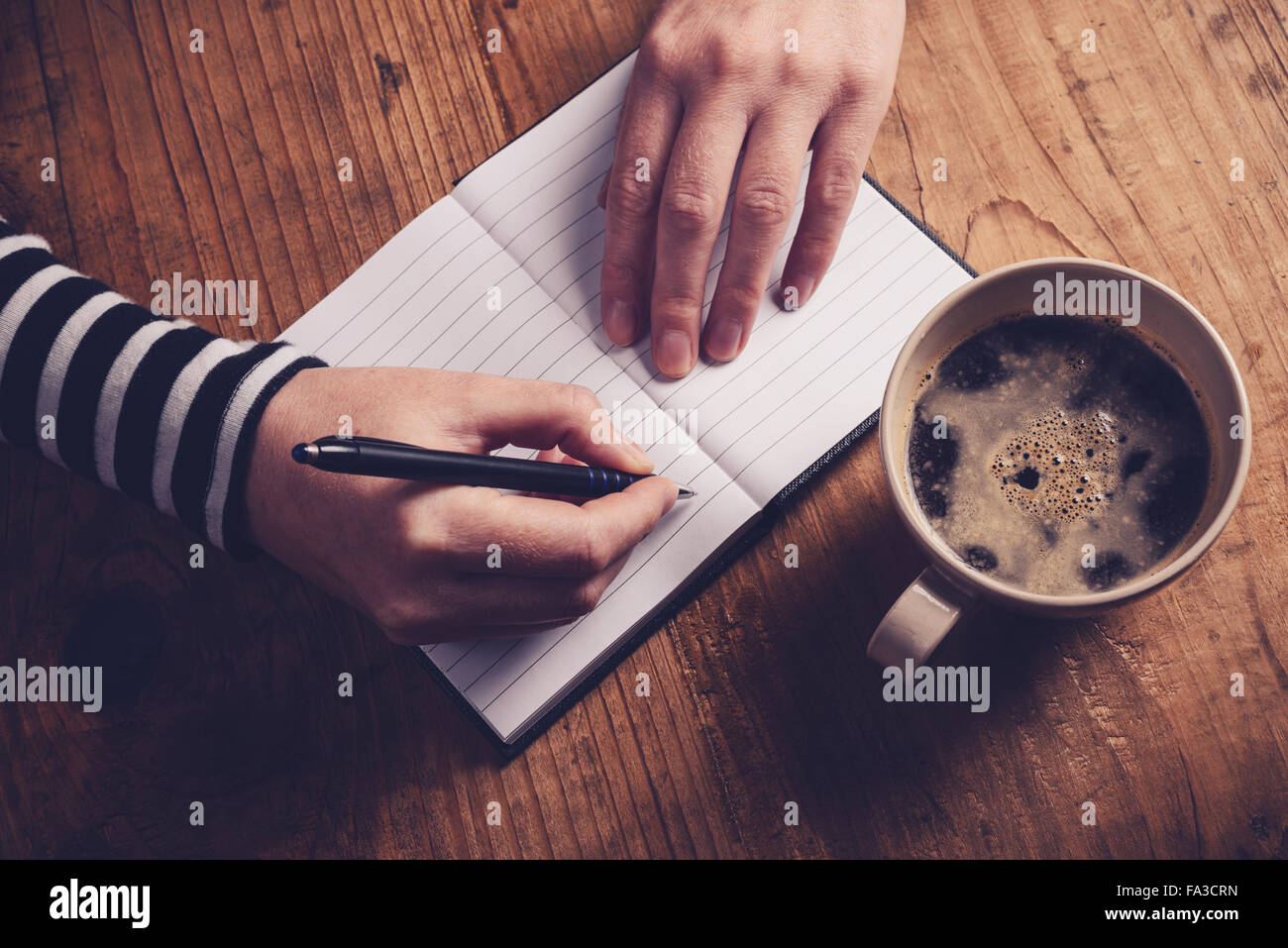 Woman drinking coffee and making a diary note, top view of female hands ...