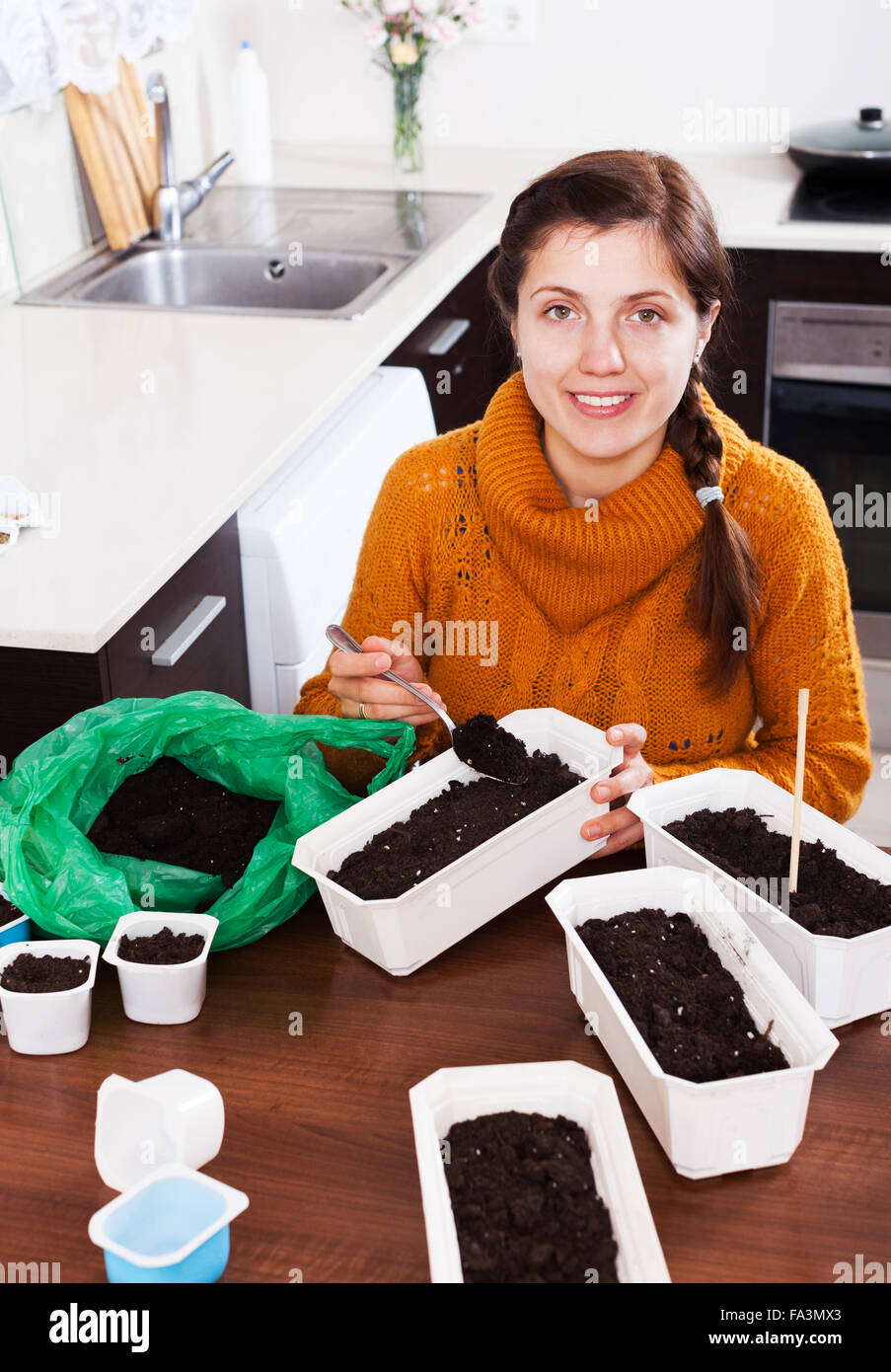 Girl sowing seeds in ground at table in kitchen Stock Photo - Alamy