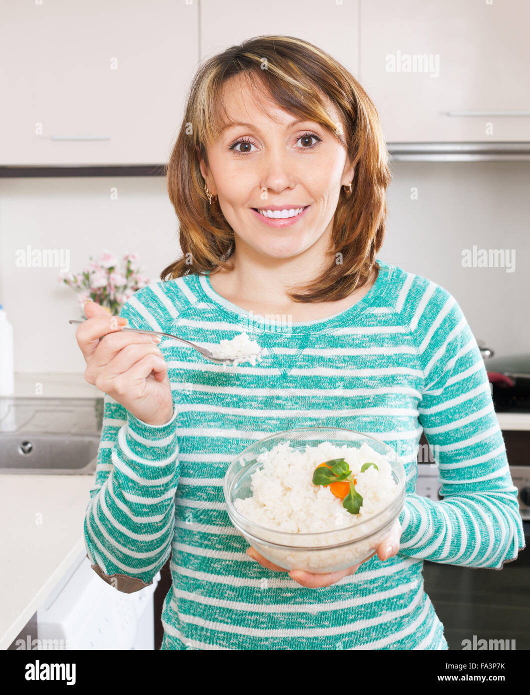 Happy woman eating boiled rice in home Stock Photo - Alamy