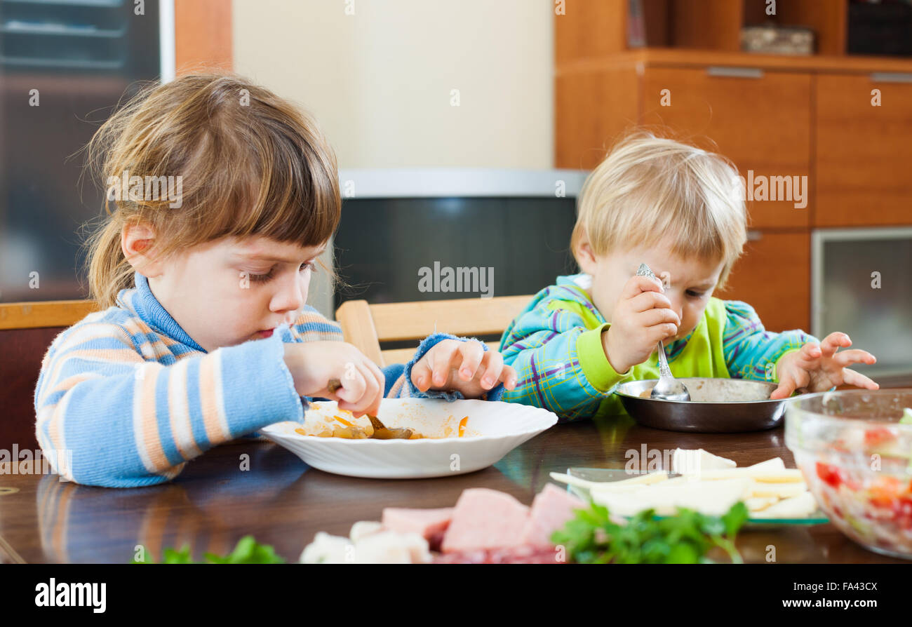 Baby girls eating at wooden table in home interior Stock Photo - Alamy