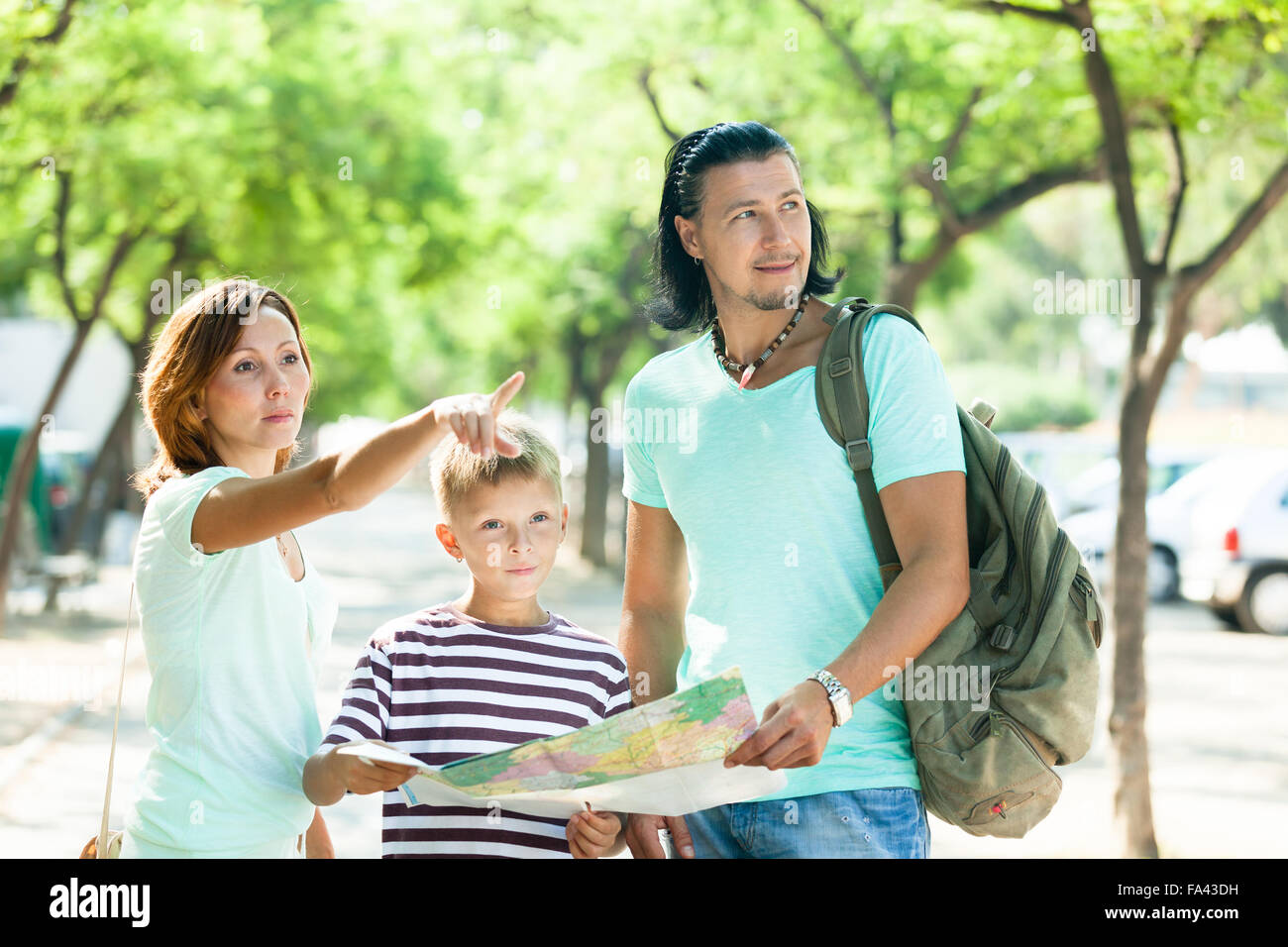 Happy family of three searching way at paper map in the city park Stock ...