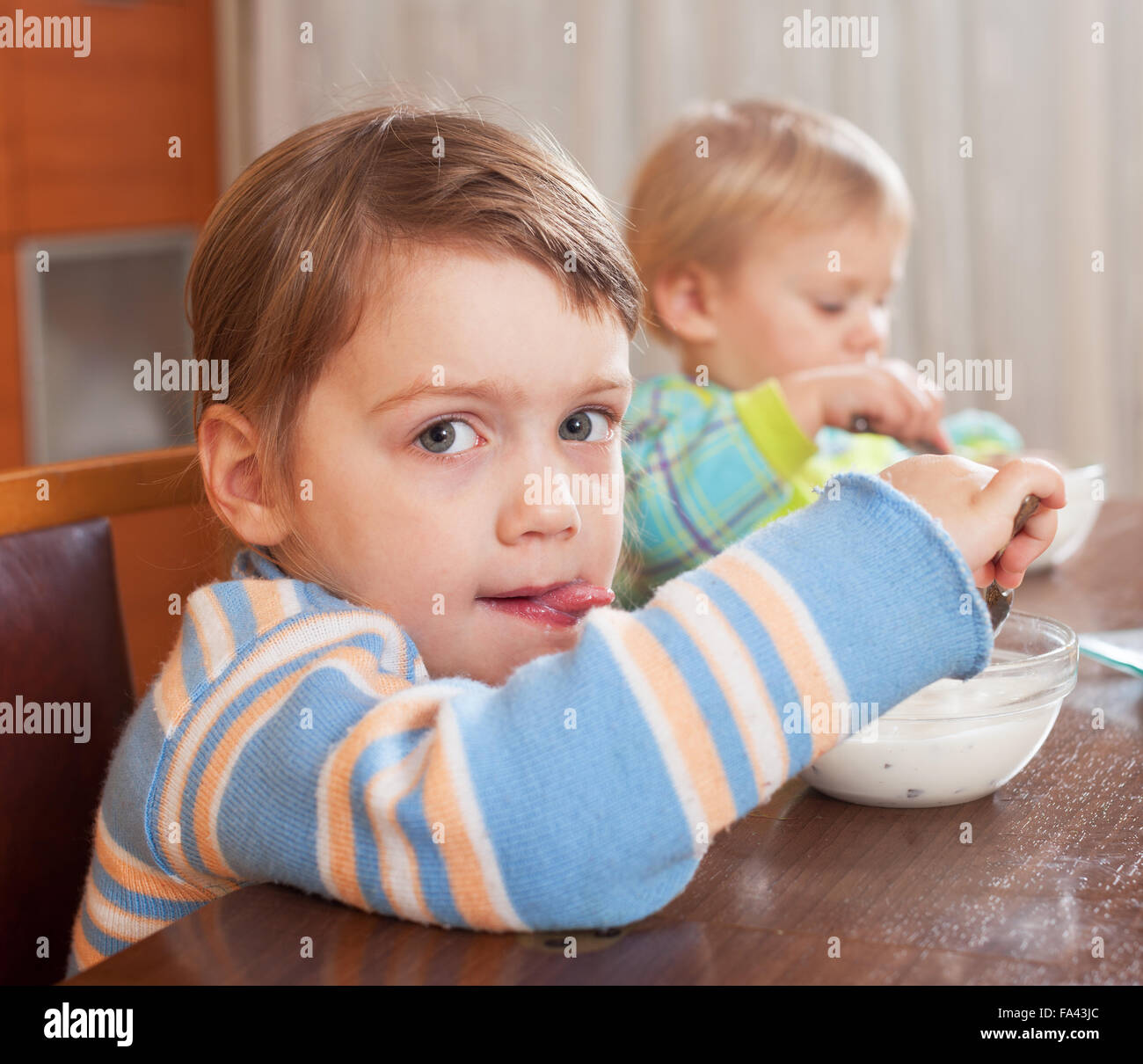 Two children eating yogurt at home in morning Stock Photo - Alamy