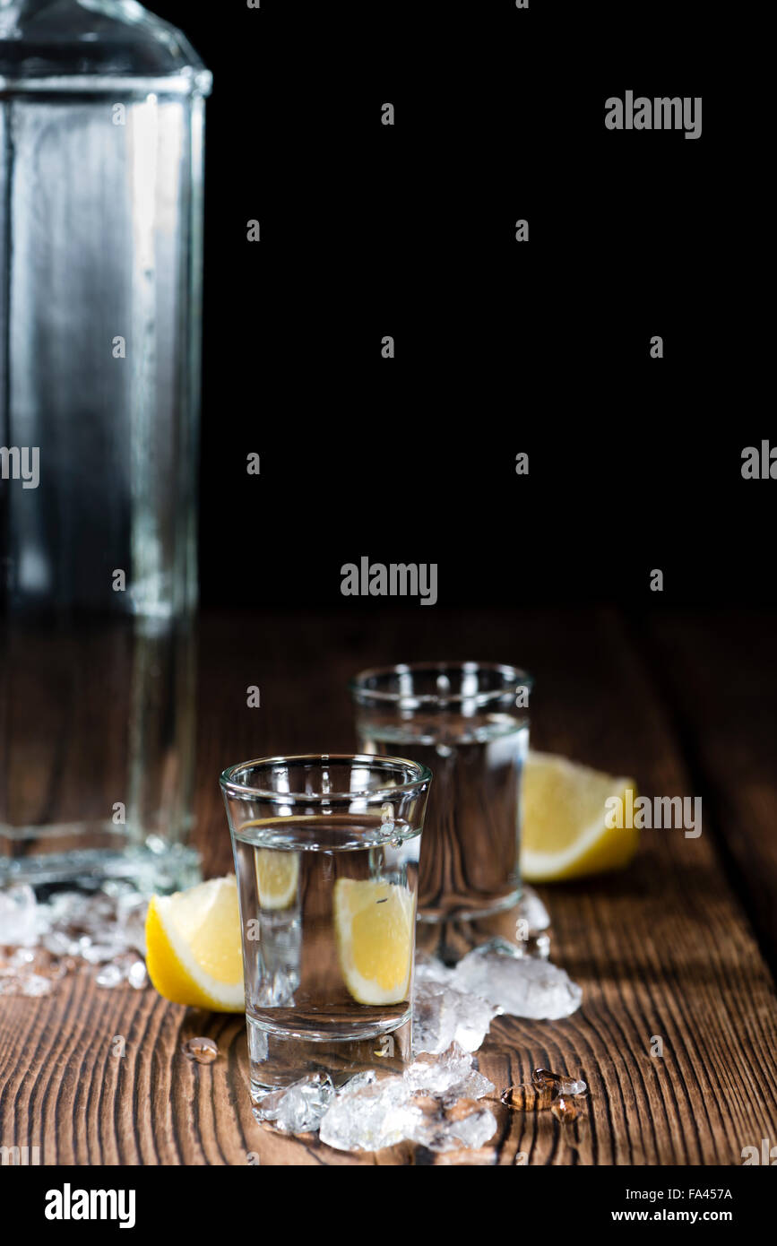 Vodka on the rocks (on an old wooden table) as detailed close-up shot ...