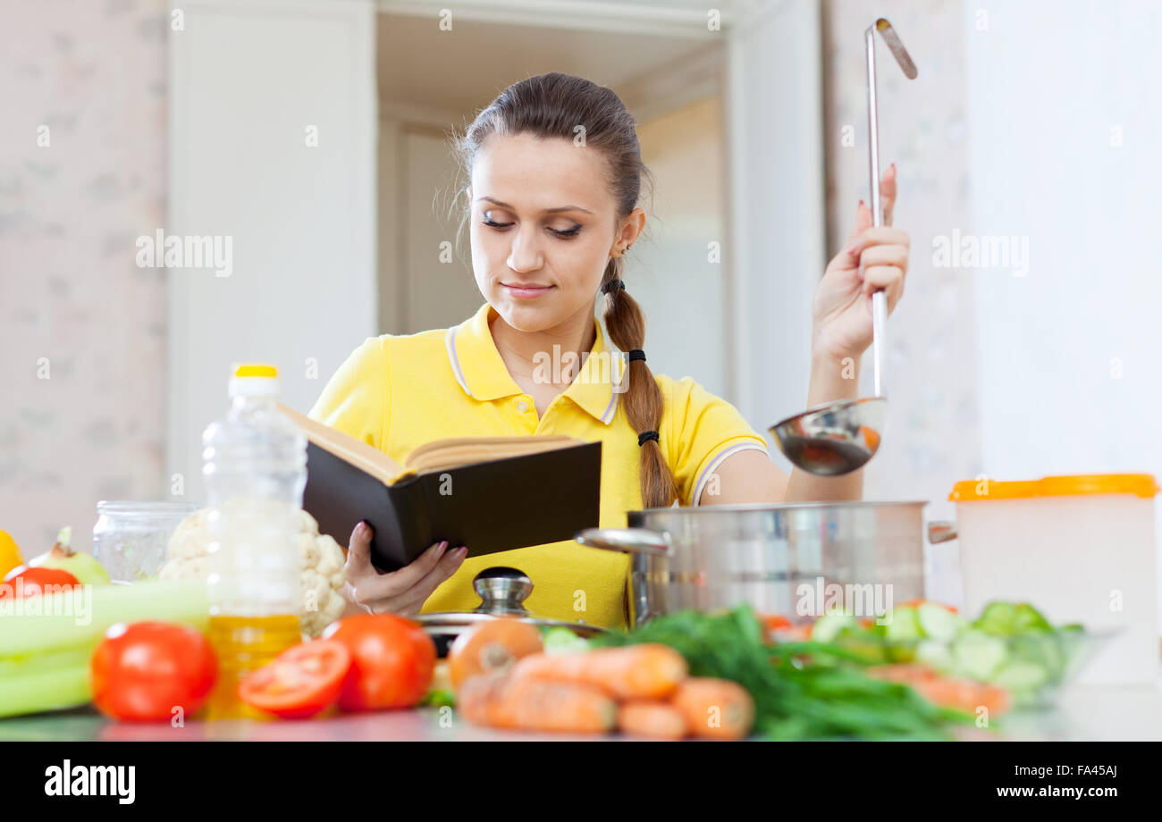 Woman cooking veggie food with book at domestic kitchen Stock Photo - Alamy