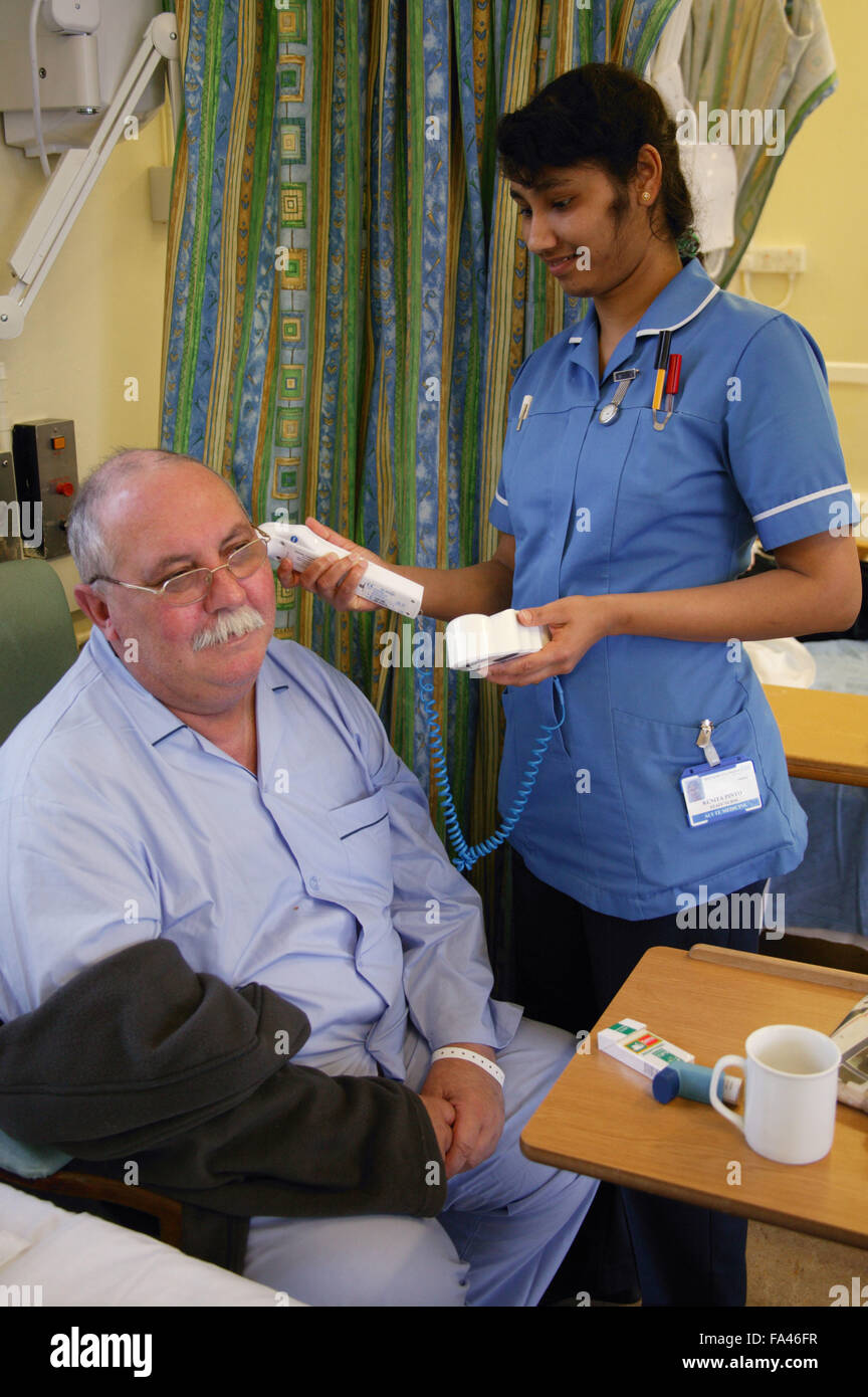 Staff nurse taking patient's temperature using a Tympanic thermometer ...