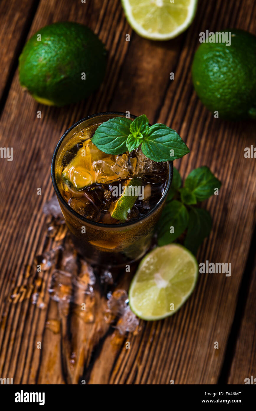 Cuba Libre longdrink with pieces of fresh lime and crushed ice on ...
