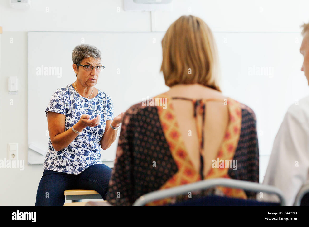 Mature teacher explaining students in hi-res stock photography and ...