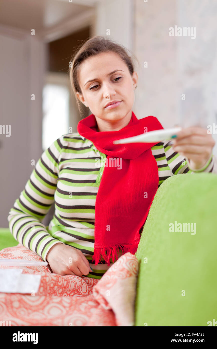 Sick woman looks by thermometer in home Stock Photo - Alamy