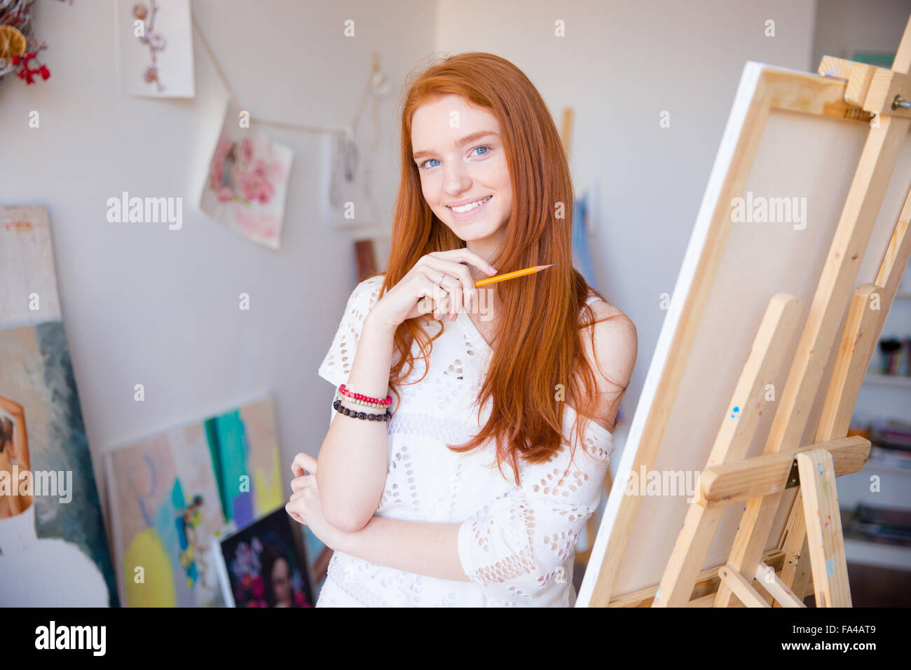 Cheerful attractive young woman artist painter sketches by pencil in ...