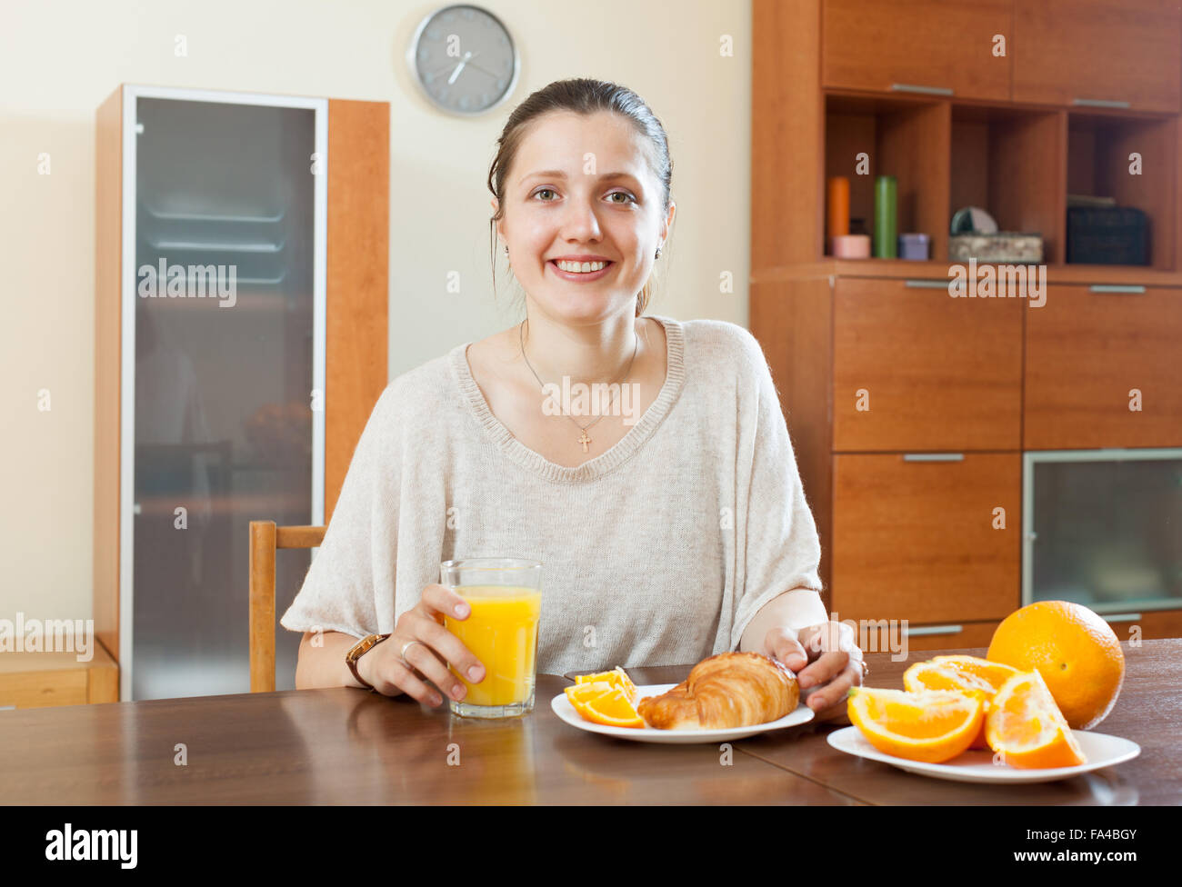 Happy adult woman having breakfast with juice in morning at interior ...