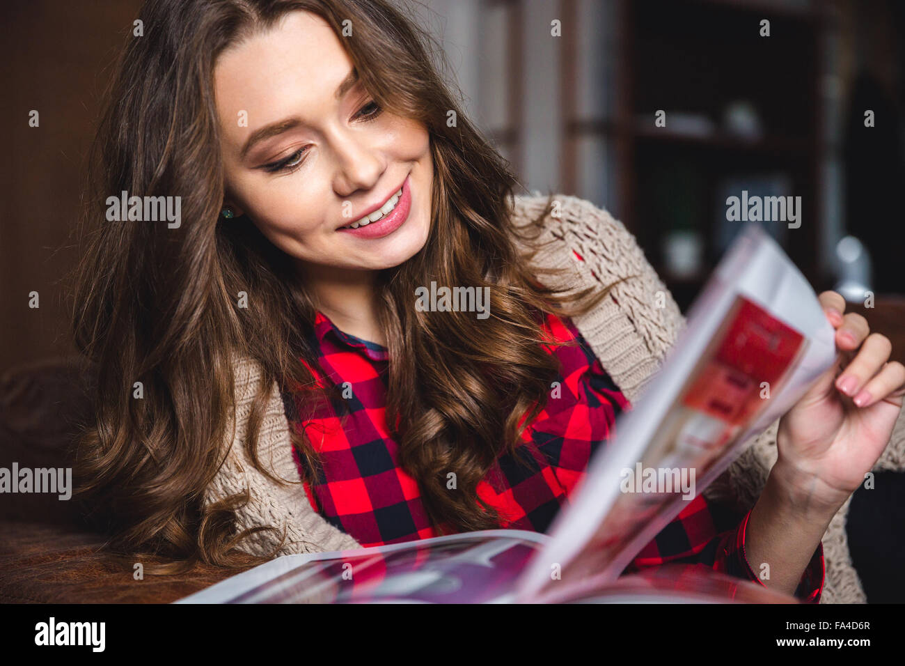 Portrait of a smiling woman reading magazine at home Stock Photo - Alamy