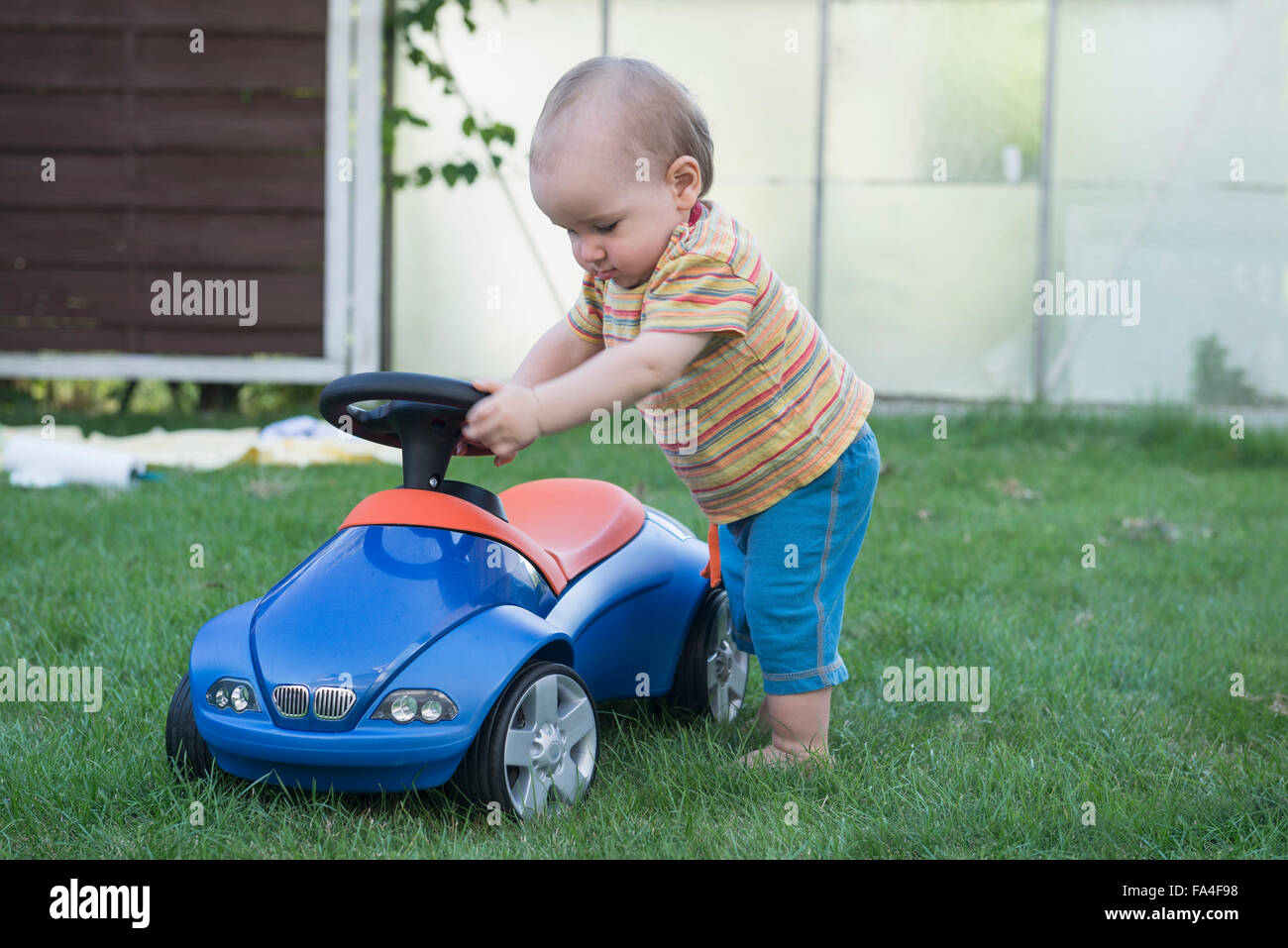 Baby boy playing with his toy car in lawn, Munich, Bavaria, Germany ...