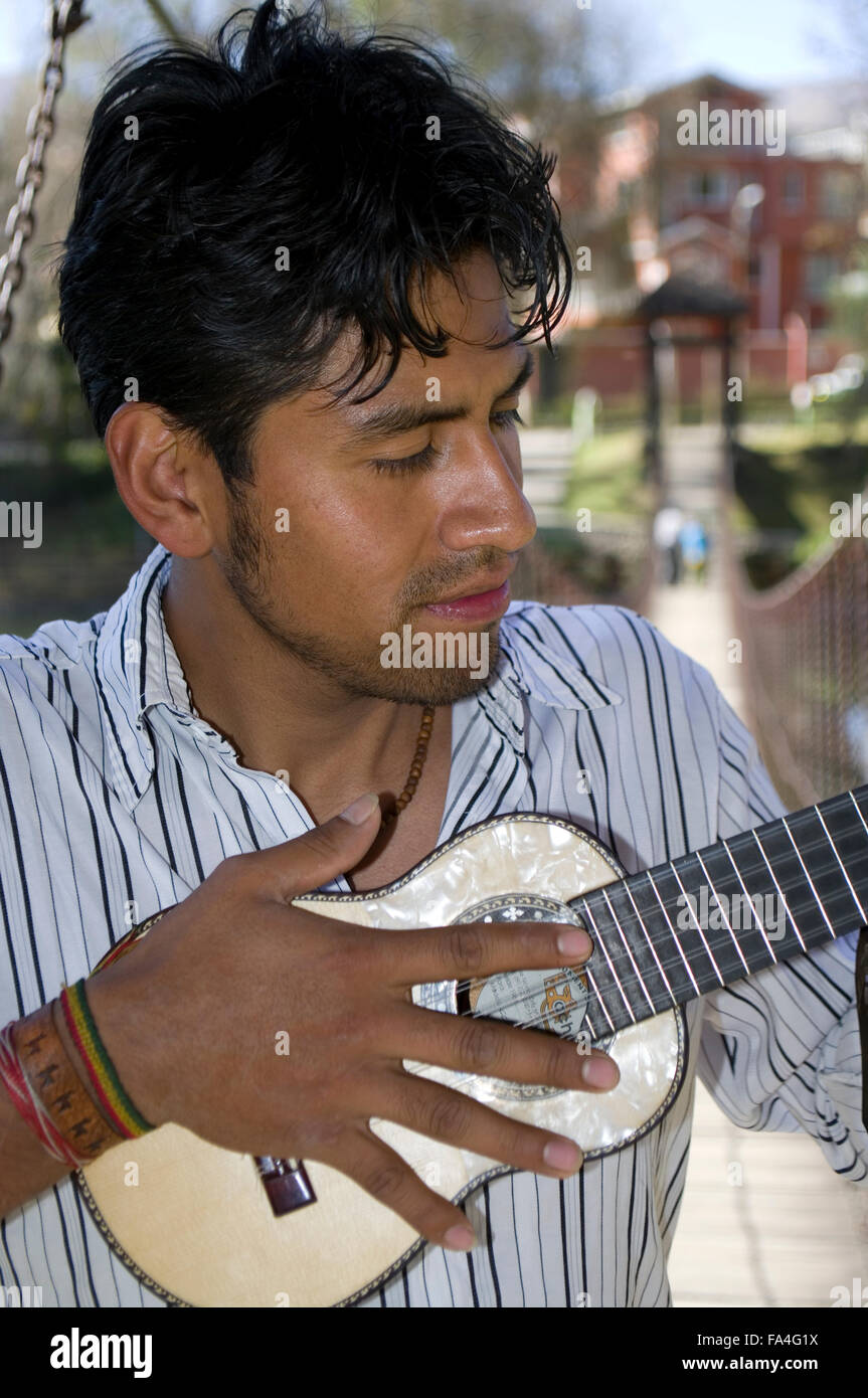 Young man in striped shirt playing the charango, a traditional Andean ...