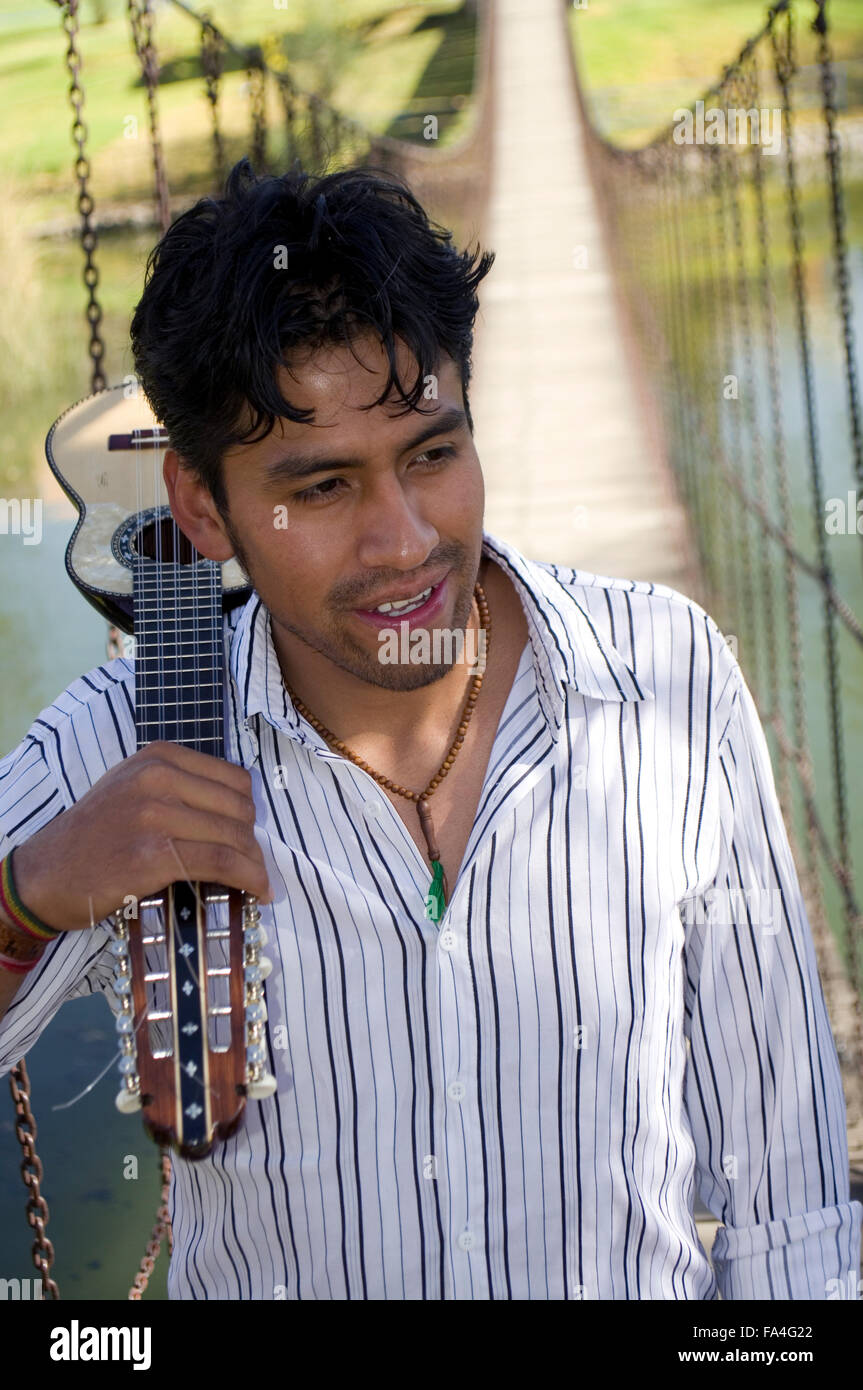 Young man smiling in a striped shirt holds a charango, a traditional ...