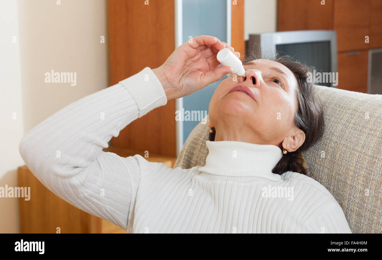 Mature woman dripping nasal drops in home Stock Photo - Alamy
