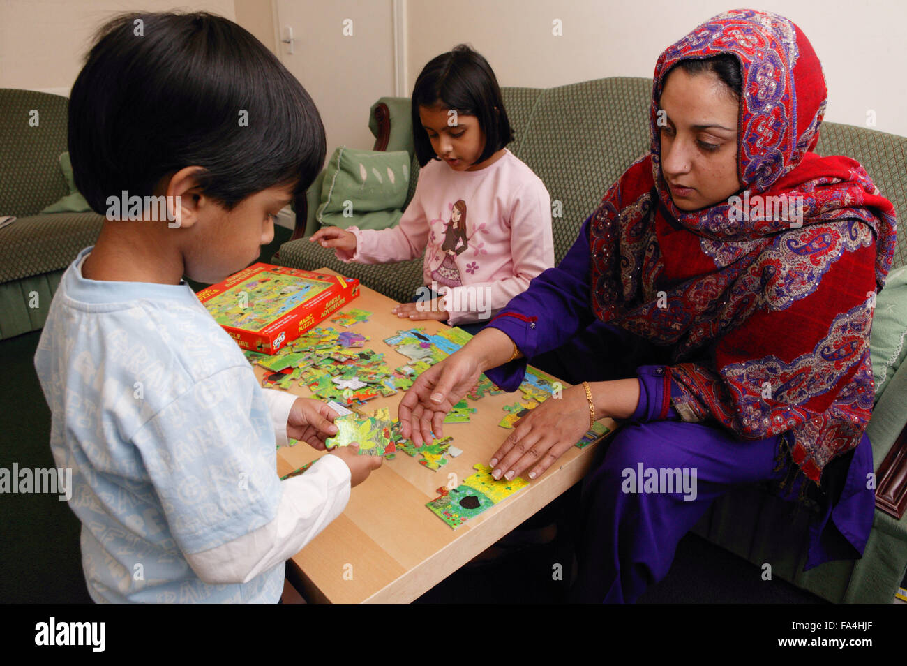 Single parent helping her young children do a jigsaw puzzle Stock Photo ...