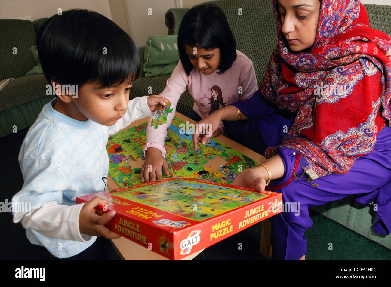 Single parent helping her young children do a jigsaw puzzle Stock Photo ...