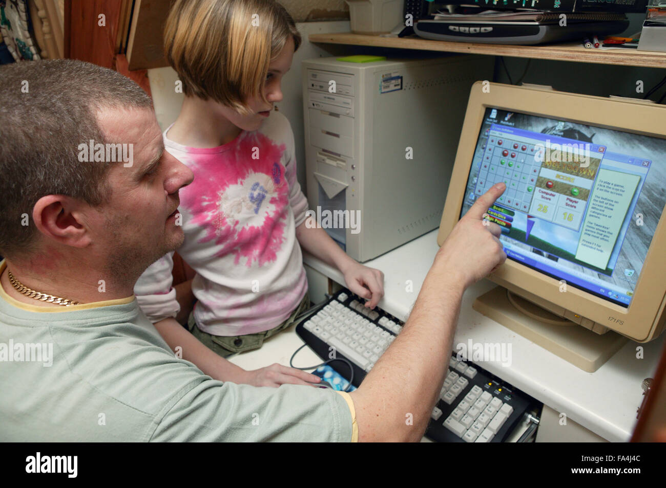 Single parent showing young daughter a game on the computer screen at ...
