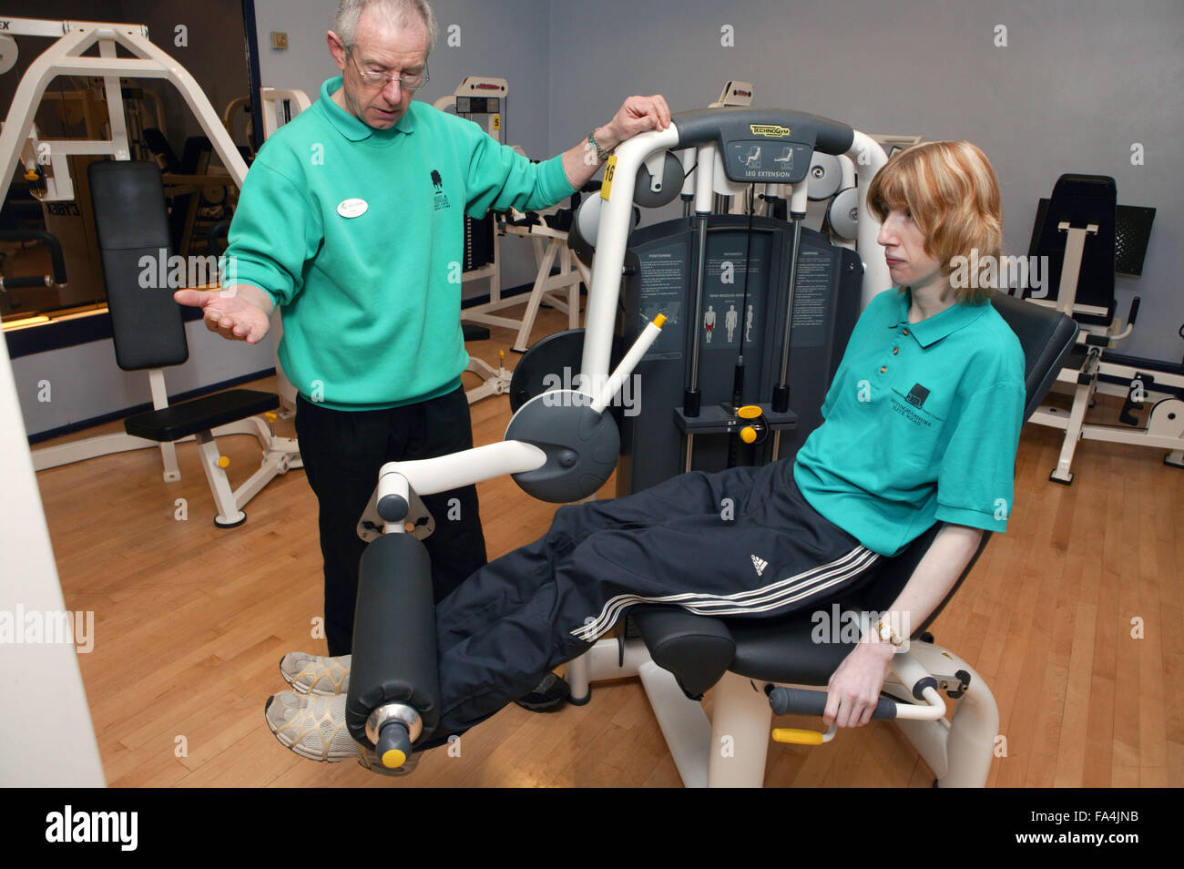 Instructor showing young woman how to use weights at an inclusive ...