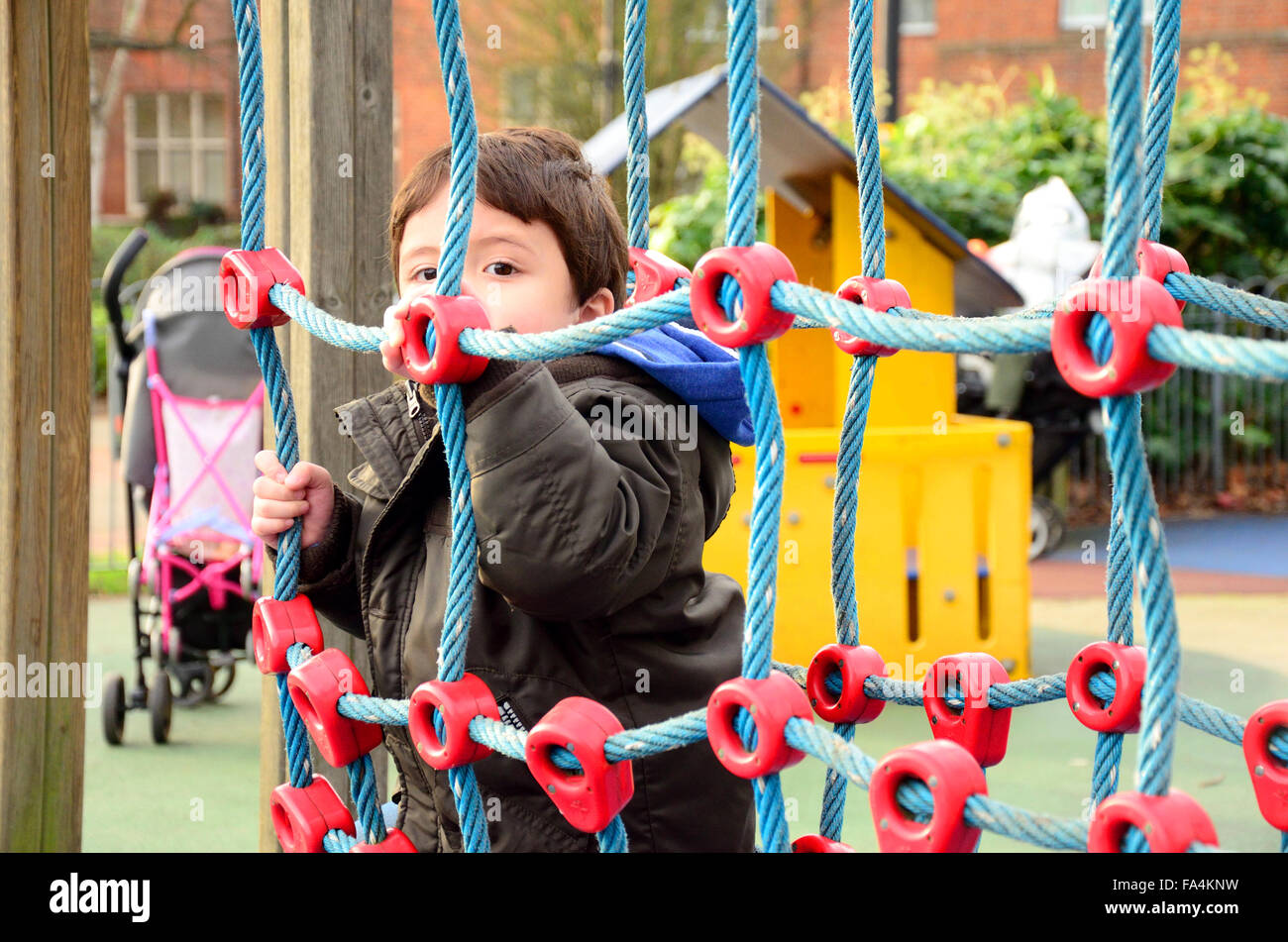 A young boy playing on a net which is part of a climbing frame in a ...