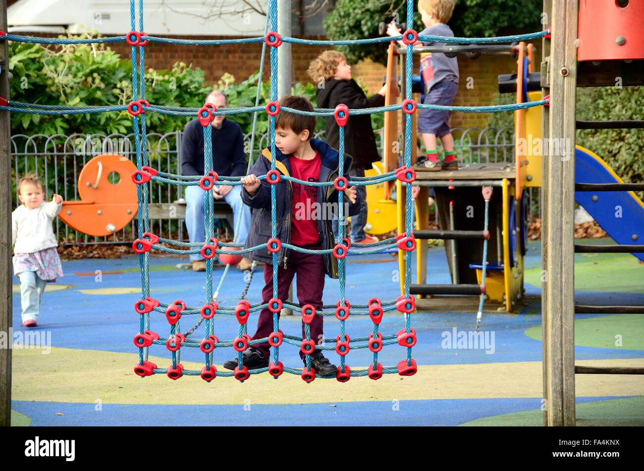 A boy climbs on a climbing net which is part of a climbing frame in a ...