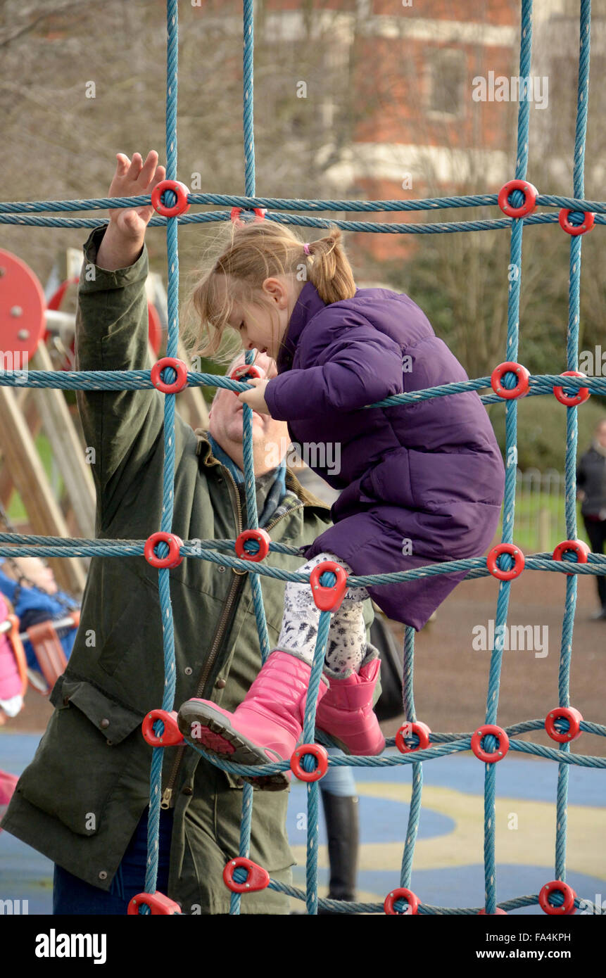 A girl climbs on netting which is part of a climbing frame with the ...