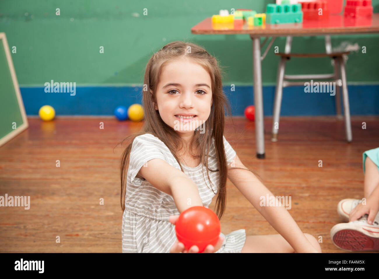 Girl showing a red ball Stock Photo - Alamy