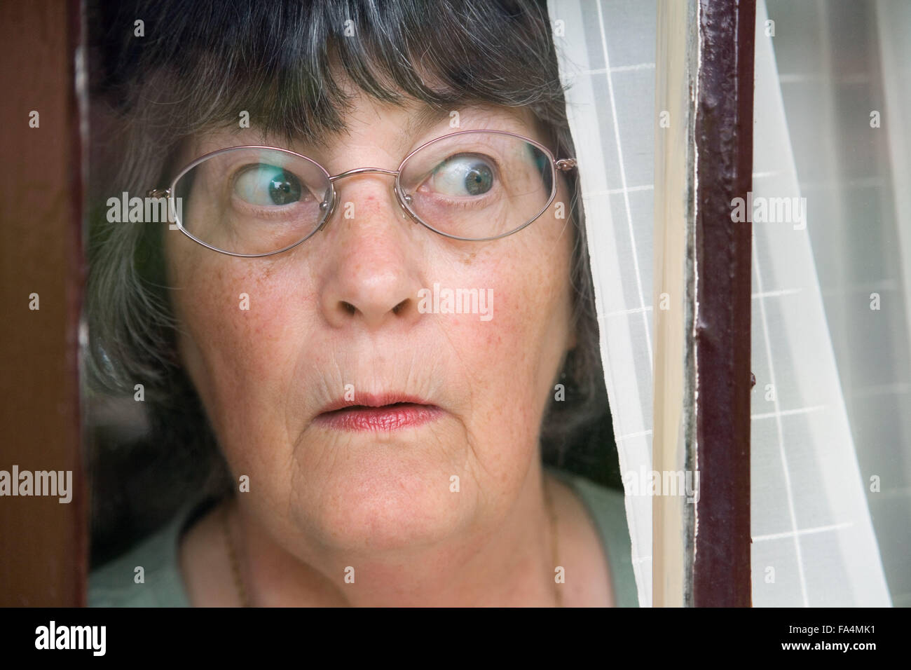 Old woman peer through curtains hi-res stock photography and images - Alamy
