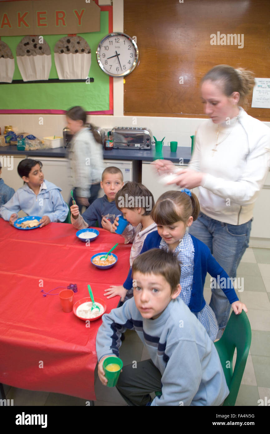Children sitting around table eating bowls of cereal at school ...