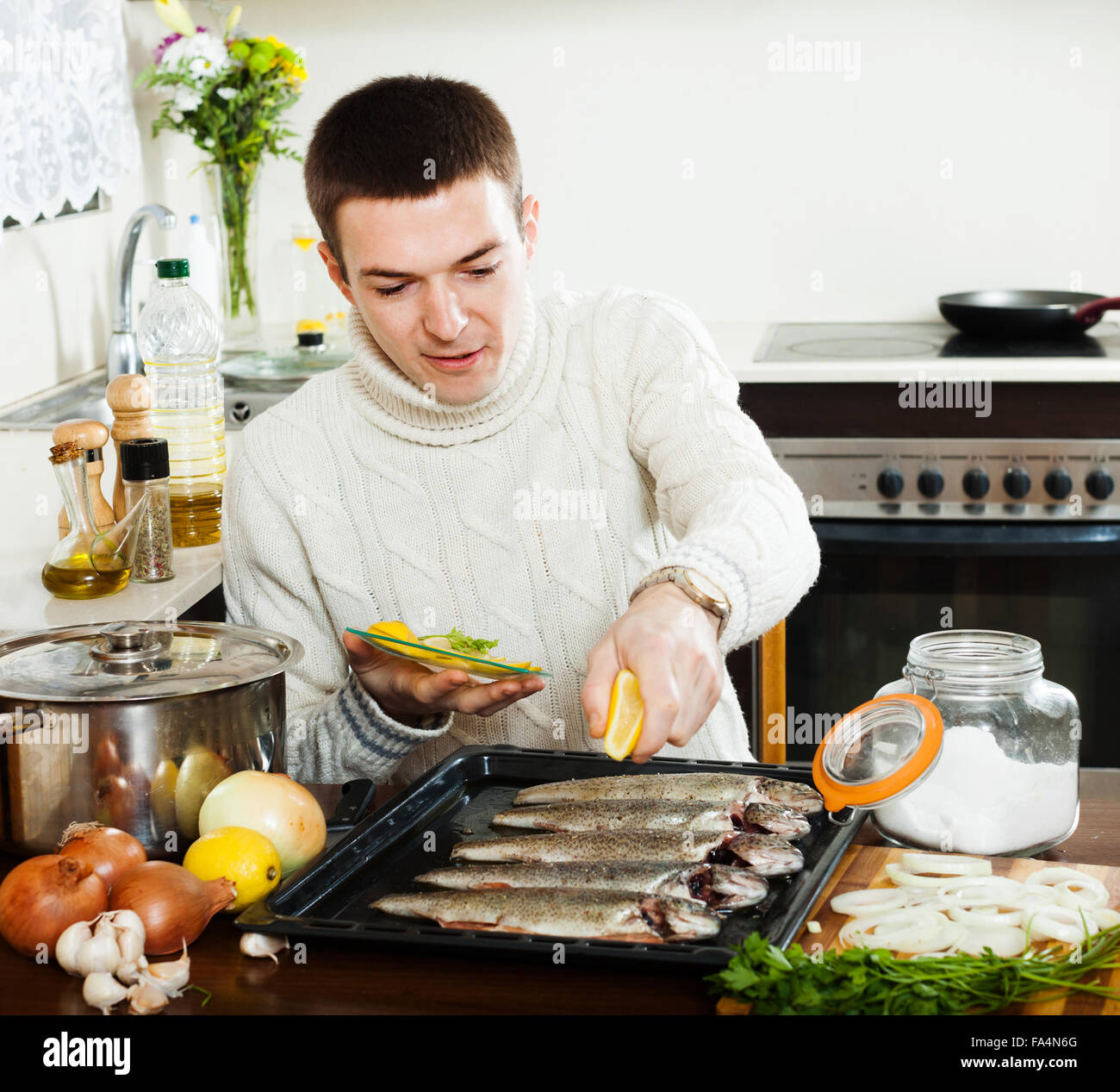 Handsome man cooking trout fish with lemon in baking shee Stock Photo ...