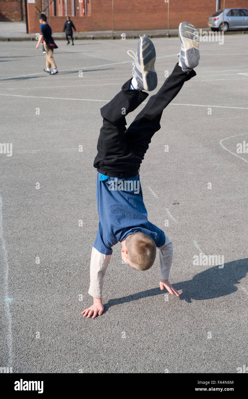 Young boy doing handstand in school playground Stock Photo - Alamy